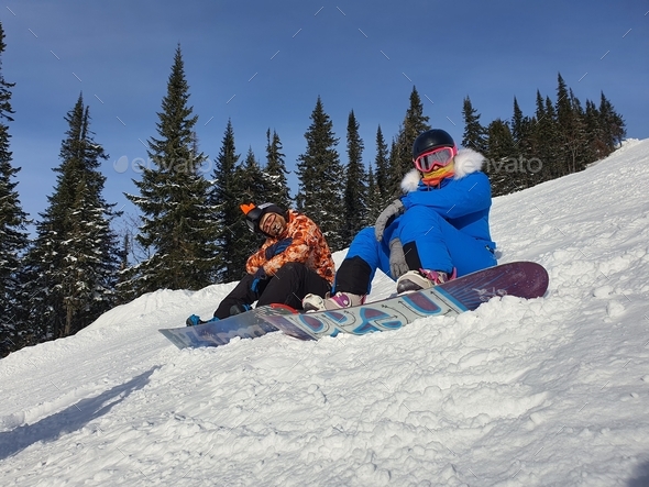 Snowboarders rest on the slope. Boy and girl snowboarding Stock Photo ...