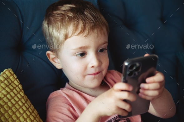 A little boy with a phone in an apartment .Children's hands holding the ...