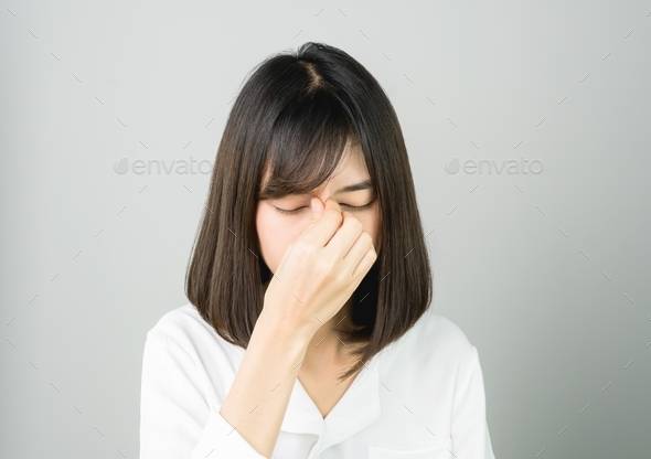 The woman is touching face between the eyebrows, to show her headache ...