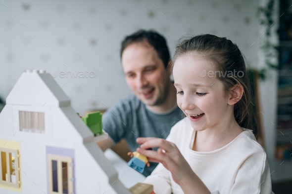 Dad and daughter play in a toy house, put together constructor, happy ...