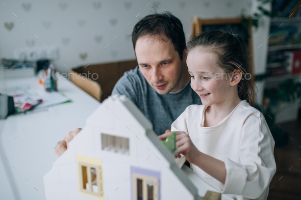 Dad and daughter play in a toy house, put together constructor, happy ...