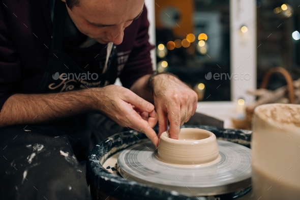 Man sculptor creating ceramics using wheel in a pottery using potter ...