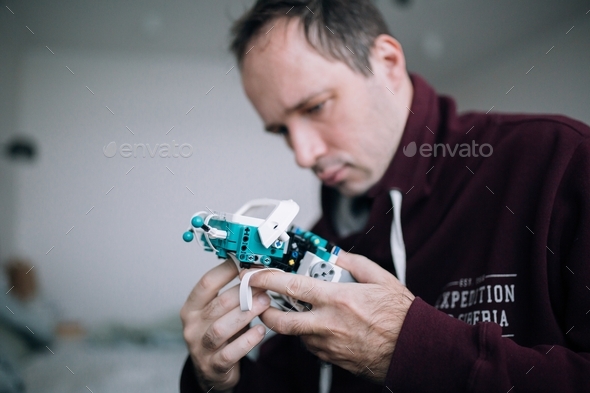 The man is engaged in robotics. A man builds and progresses a robot ...