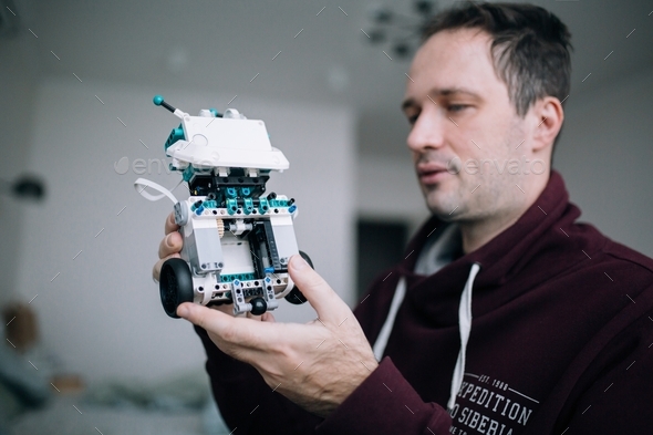 The man is engaged in robotics. A man builds and progresses a robot ...