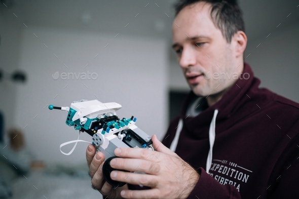 The man is engaged in robotics. A man builds and progresses a robot ...