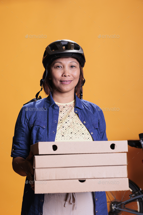Takeout delivery woman wearing helmet and pizzeria uniform carrying ...