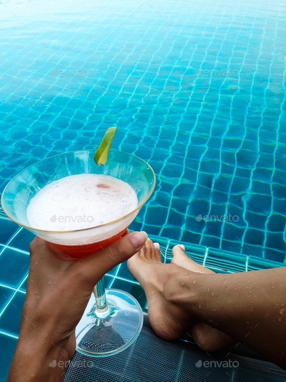 Drinking alcoholic cocktails at the swimming pool Stock Photo by Leonteena