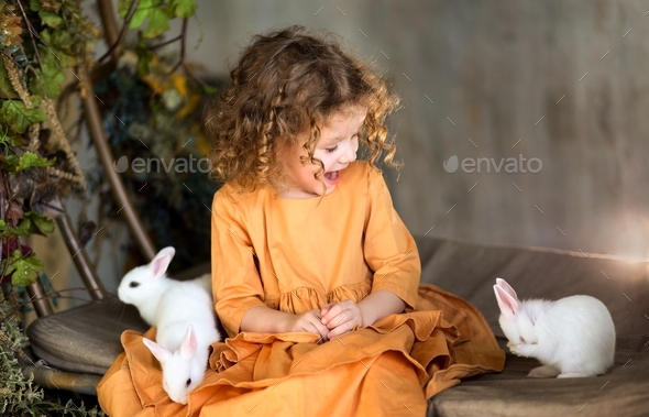 A beautiful girl in a yellow dress is sitting on a bench, with little ...