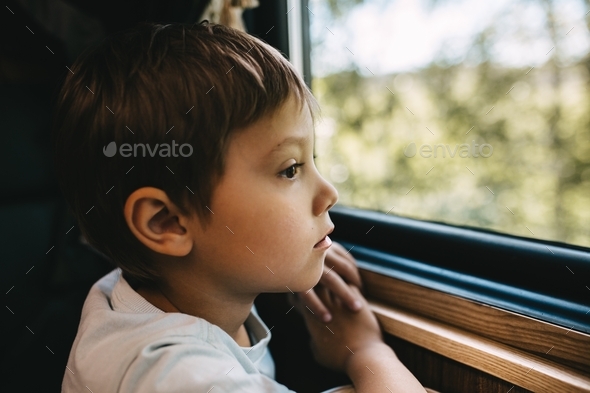 Cute little boy looking into window travelling by train Stock Photo by ...