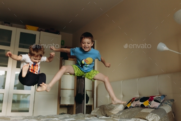 Brothers having fun at home jumping on bed Stock Photo by uraneva ...
