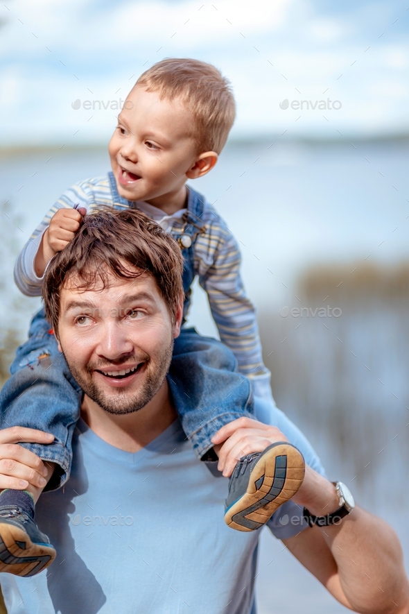 Father and son. Boy sitting on men’s shoulders Stock Photo by uraneva
