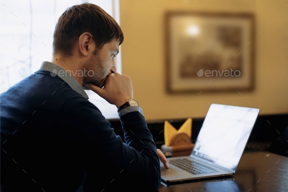 young handsome intelligent attentive man cheching his email on laptop ...