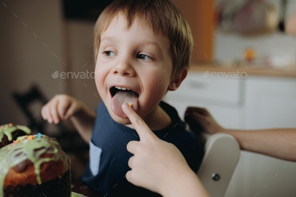 Cute little boy tasting sugar icing while decorating Easter cake Stock ...