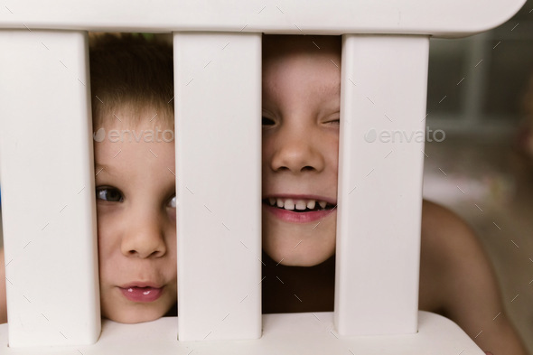 Cute brothers boys peeking out from behind chair . Smiling happy kids ...