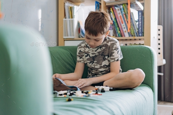 Little caucasian boy constructing using instructions Stock Photo by uraneva