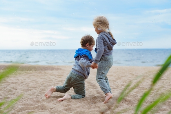 Brother and little sister during summer vacations having fun on sandy ...