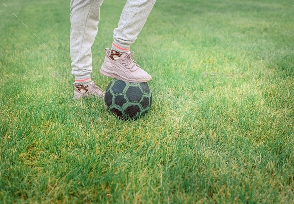 Cute little girl playing football with soccer ball on green lawn in ...