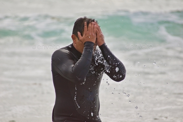 NOMINATED A surfer wearing a wetsuit washes his face after working hard ...