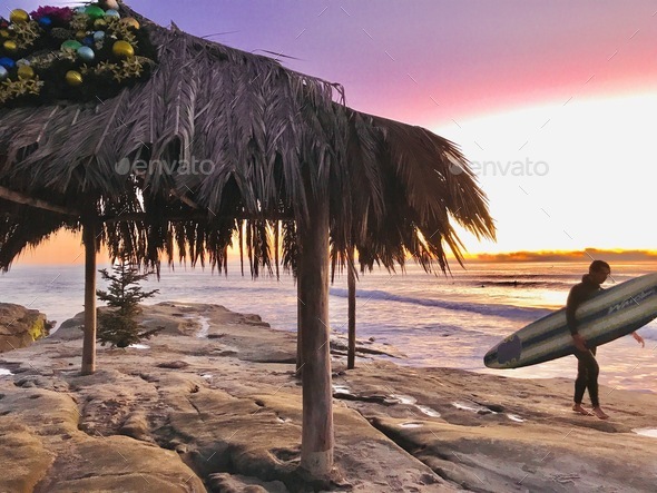 Surfer walking with his longboard past the iconic Surf hut at Windansea ...