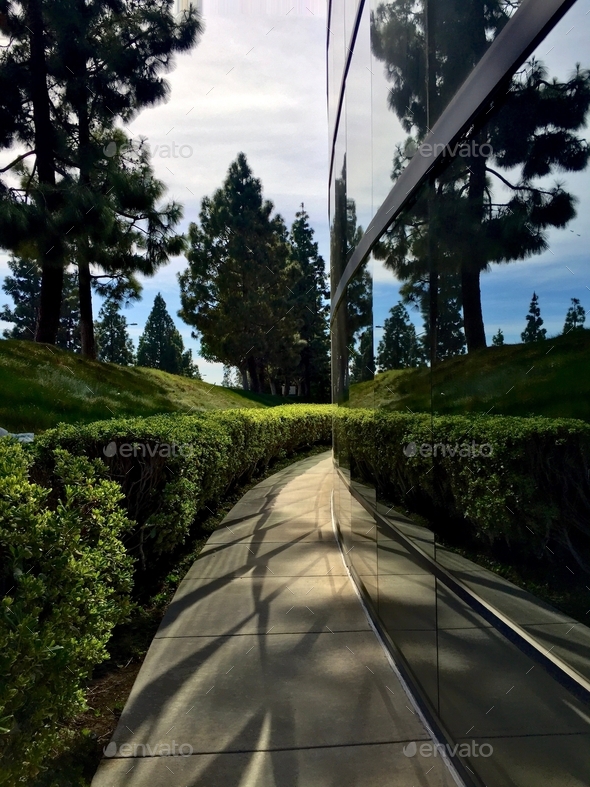 Walking path around a modern building with curved, mirrored glass ...