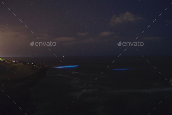 The red tide with blue bioluminescence on a rolling wave under a night ...