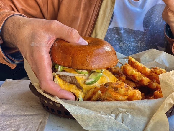 Person holding a delicious cheeseburger about to take a bit and eat it ...