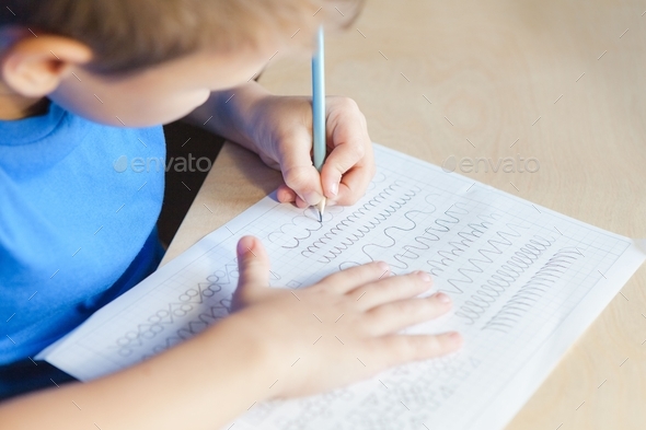 Close up of cute boy tracing lines with pencil Stock Photo by OlgaKhorkova