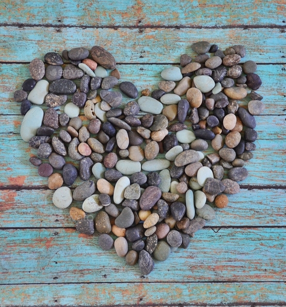 Heart shape for love formed of rocks on a rustic blue wooden background ...