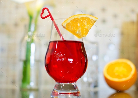 Colorful red alcohol cocktail drink in a glass with orange slice ...