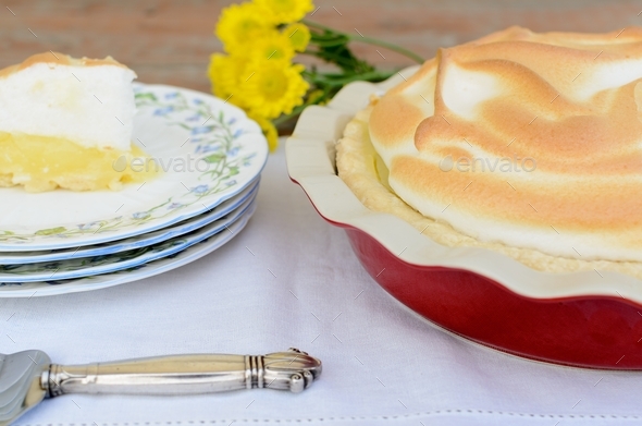 Lemon meringue pie in a red pie dish with a slice on a vintage plate ...