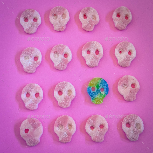 Colorful skull shaped gummy candies on a pink background with one ...