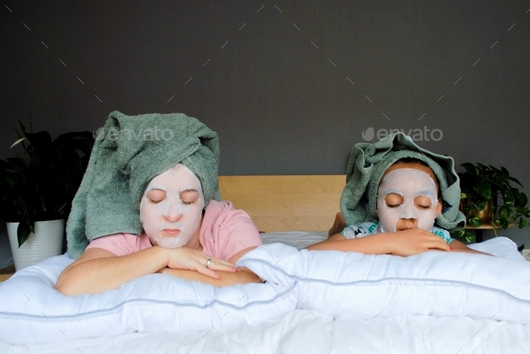 Little black of mixed girl and mother relaxing on bed on a spa day ...