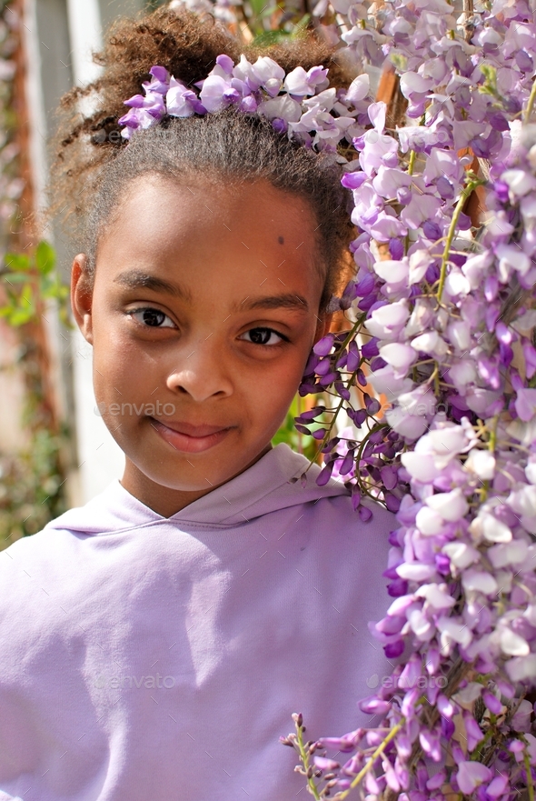 Portrait of Generation Z girl in front of purple wisteria flowers ...