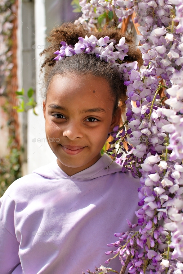 Portrait of Generation Z girl in front of purple wisteria flowers ...