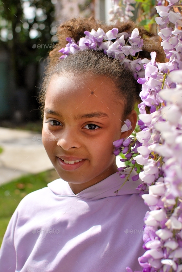 Portrait of Generation Z girl in front of purple wisteria flowers ...