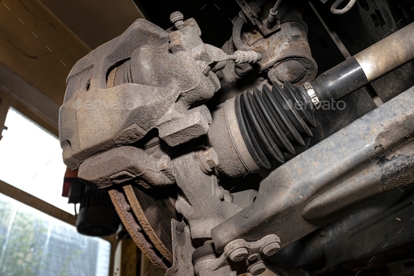 Drive shaft covered with rubber, visible disc and brake caliper, seen ...