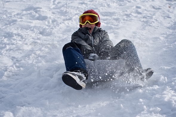 Little boy in the ski glasses have fun on sleds and descend from the ...