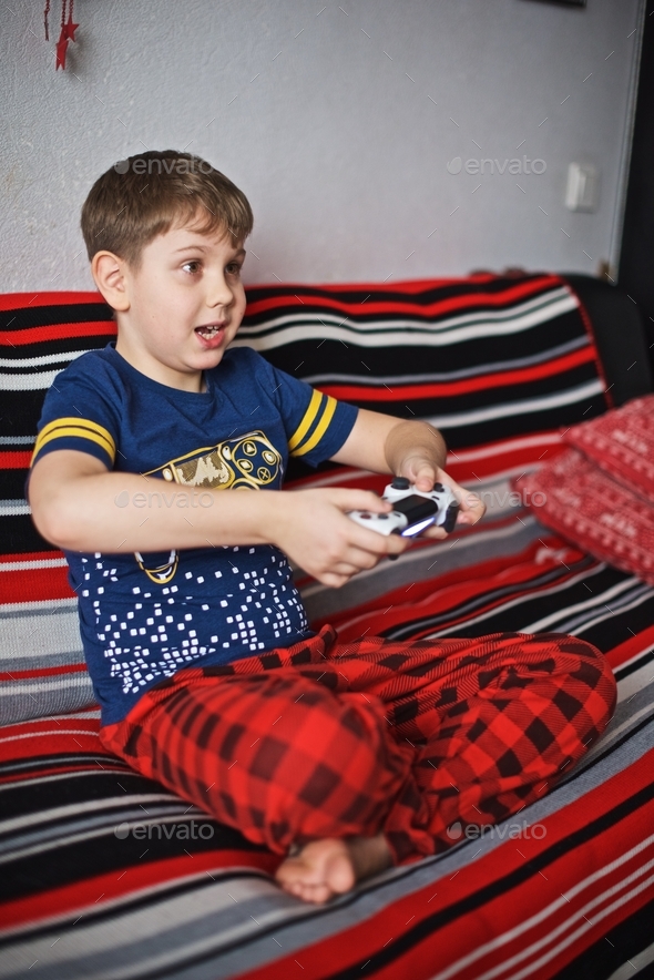 Young boy sitting very nervously on the sofa during video Game Stock ...