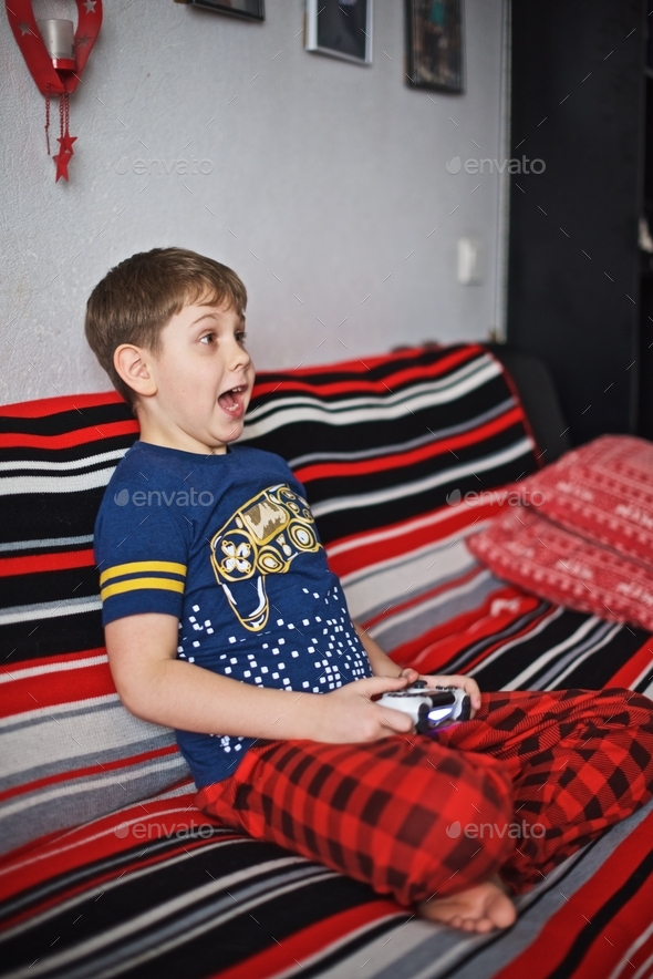 Young boy sitting very nervously on the sofa during video Game Stock ...