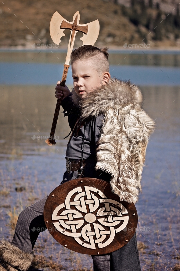 Young viking warrior in the Wolfskin cloak with wooden shield and axe ...