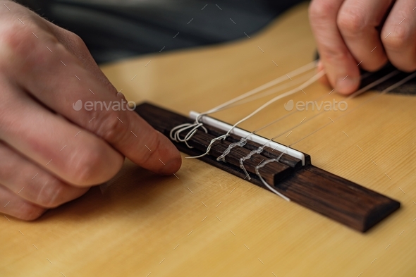 Male hands pulling a new string on an acoustic guitar Stock Photo by ...