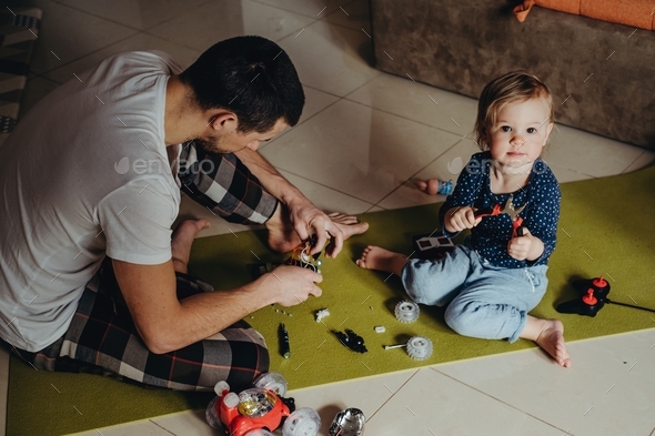 Little daughter holds pliers in her hands, helps dad fix a toy Stock ...