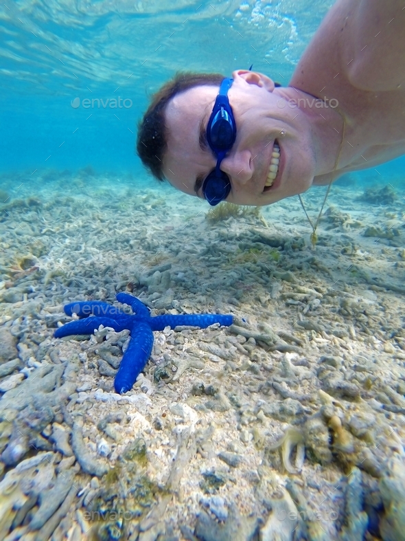 A smiling guy at the bottom of the sea next to a blue starfish. Stock ...
