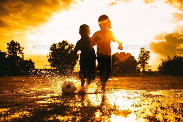 Kids playing soccer football on the wet field after the raining. Stock ...