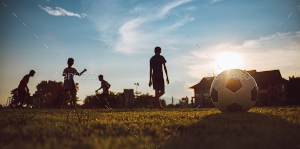 Kids playing soccer football under the sunset Stock Photo by natee127