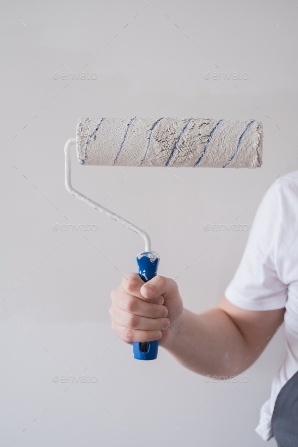 Man's hand holding a roller for painting the walls Stock Photo by rekaolya