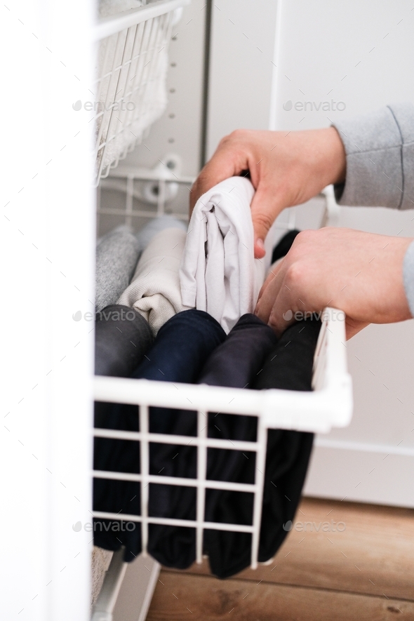 Man sorting clothes in baskets room cleaning Stock Photo by rekaolya