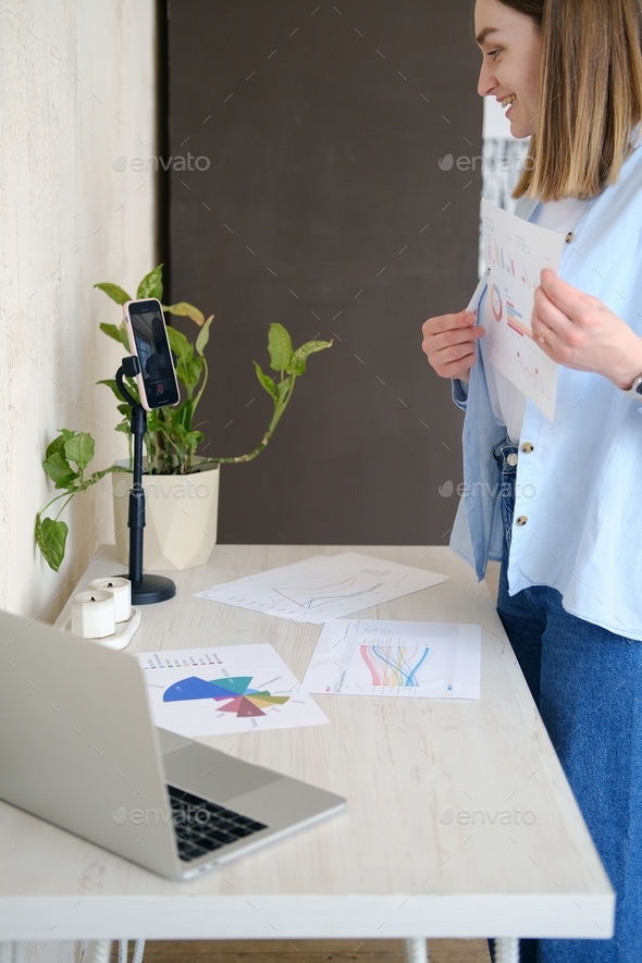 Joyful young woman holding graphs and charts and leading business ...