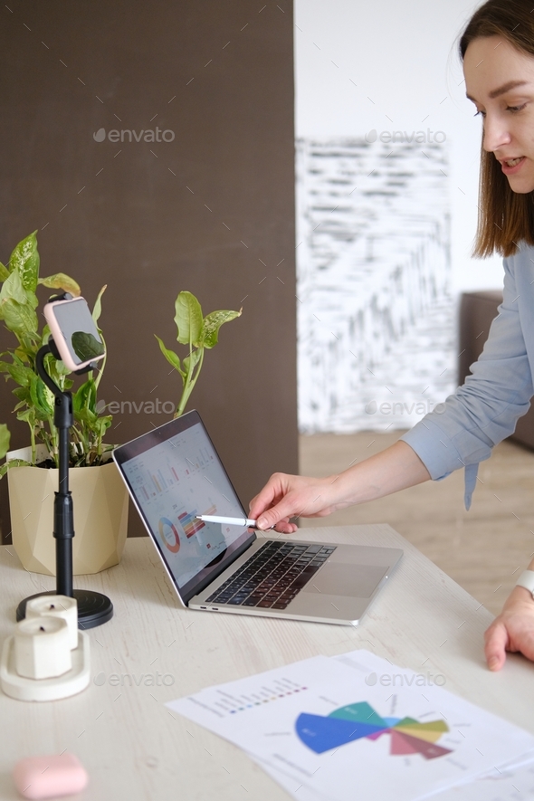 Serious young woman holding graphs and charts and leading business ...