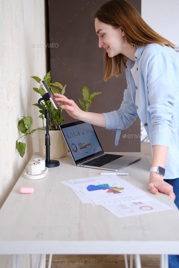 Joyful young woman holding graphs and charts and leading business ...